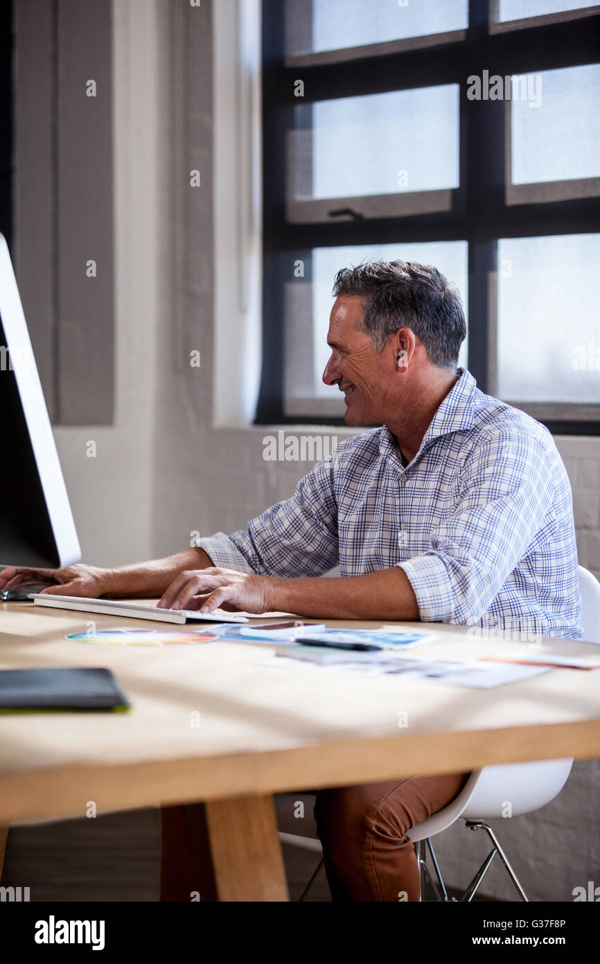 Portrait of businessman smiling and working on his computer Stock Photo ...