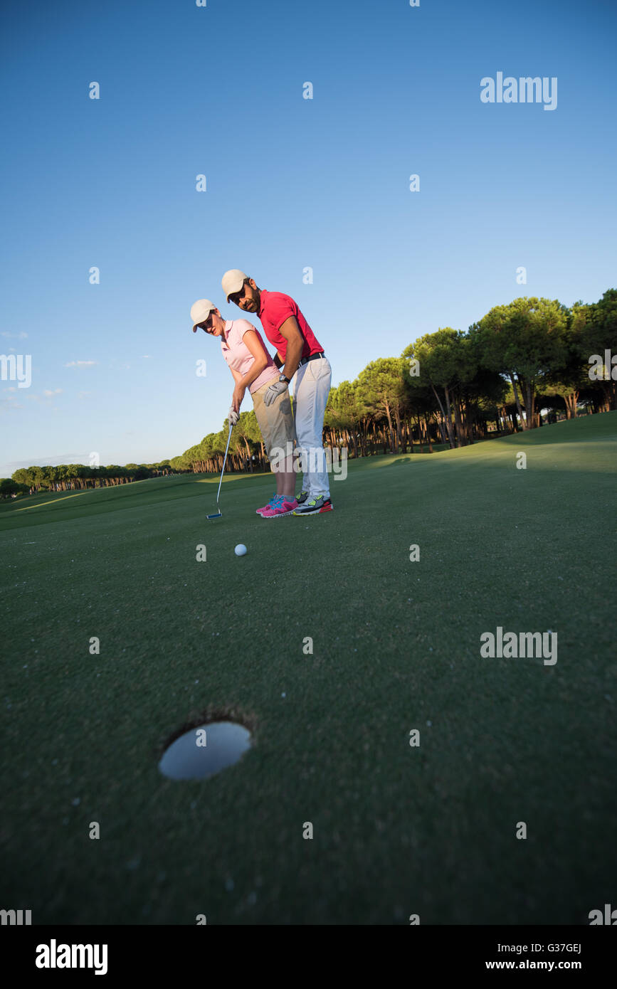 male golf instructor teaching female golf player, personal trainer ...