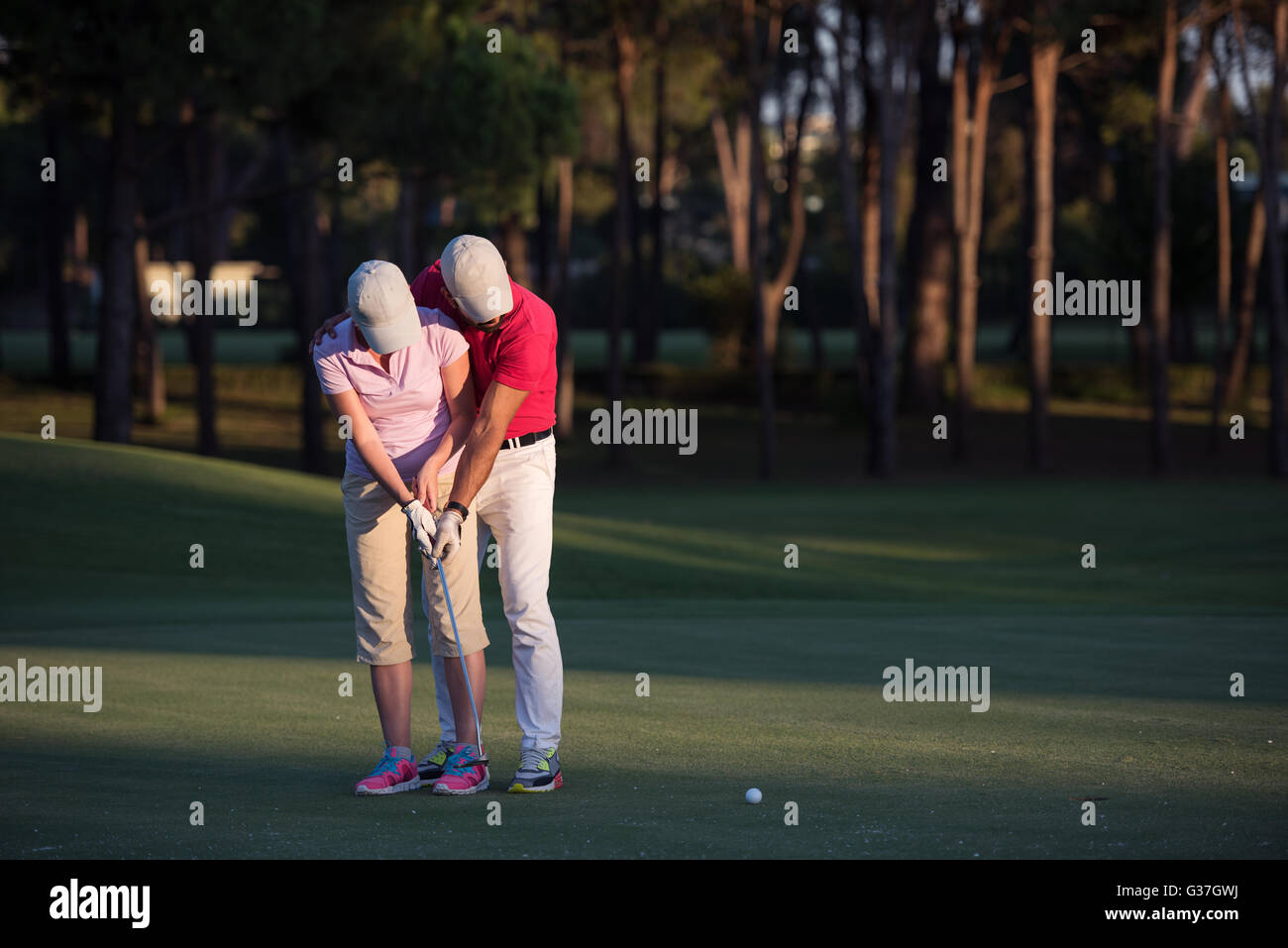 male golf instructor teaching female golf player, personal trainer ...