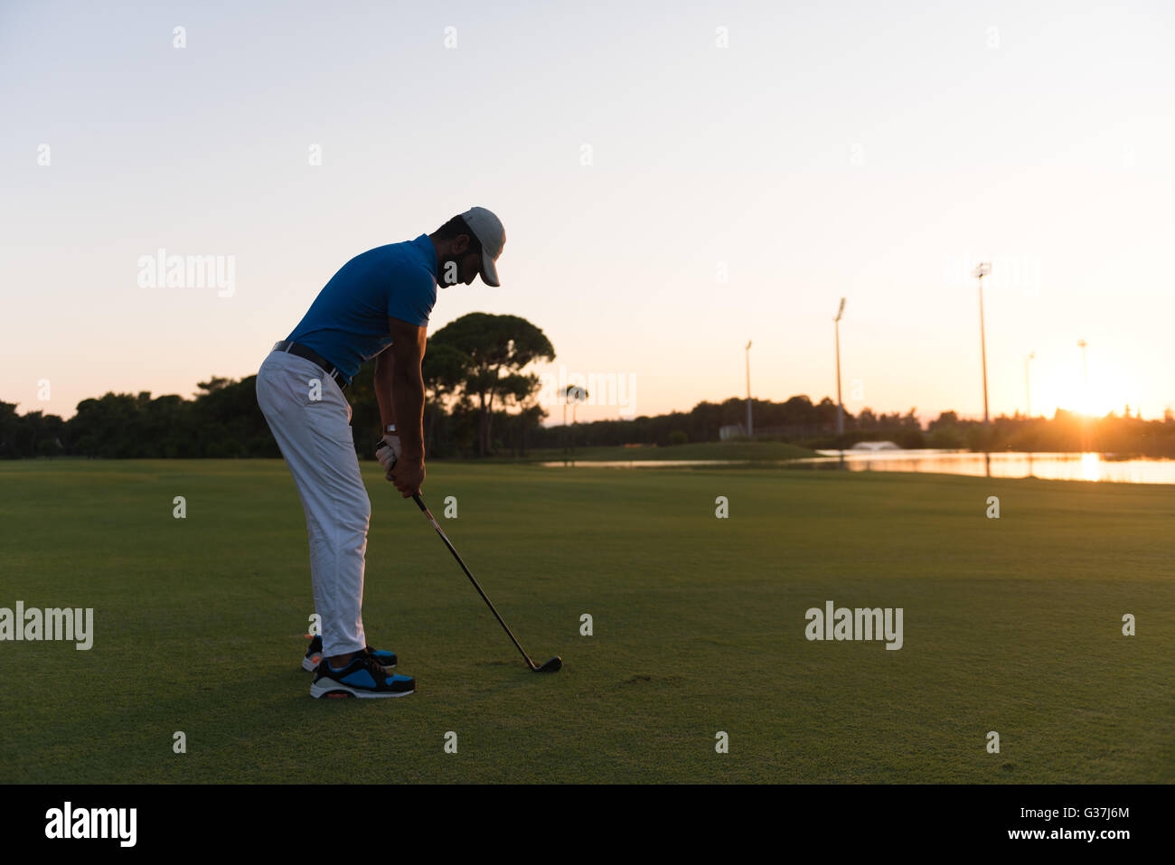 golfer hitting long shot with driver on course at beautiful sunset ...