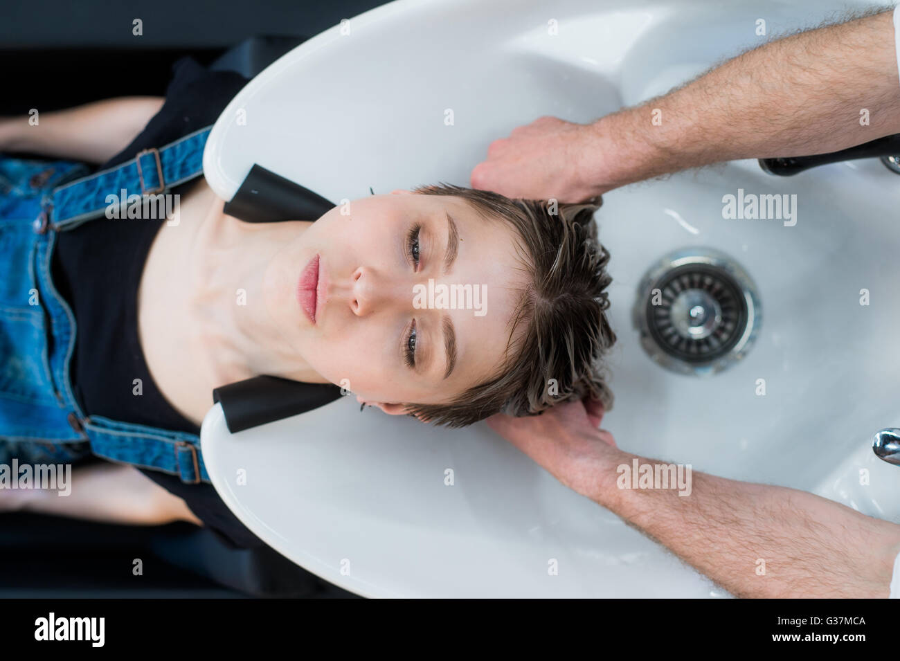 Stylist at work - hairdresser washing hair to the teen girl customer ...