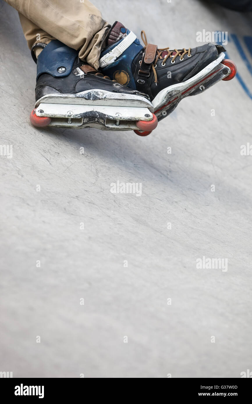 Feet of rollerblader wearing aggressive inline skates sitting on a ...