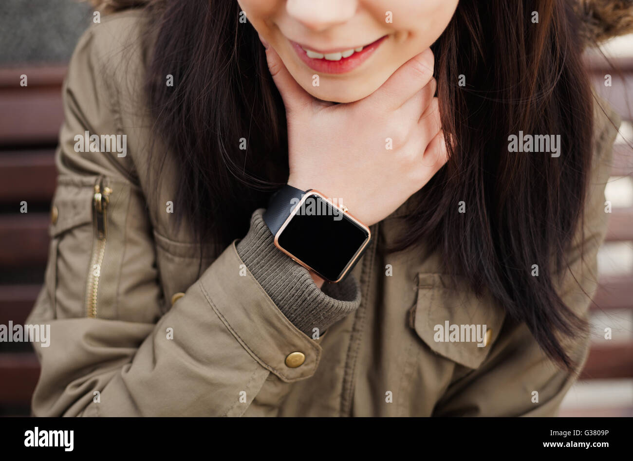 Smiling young girl in parka coat wearing trendy smart watch. This new ...
