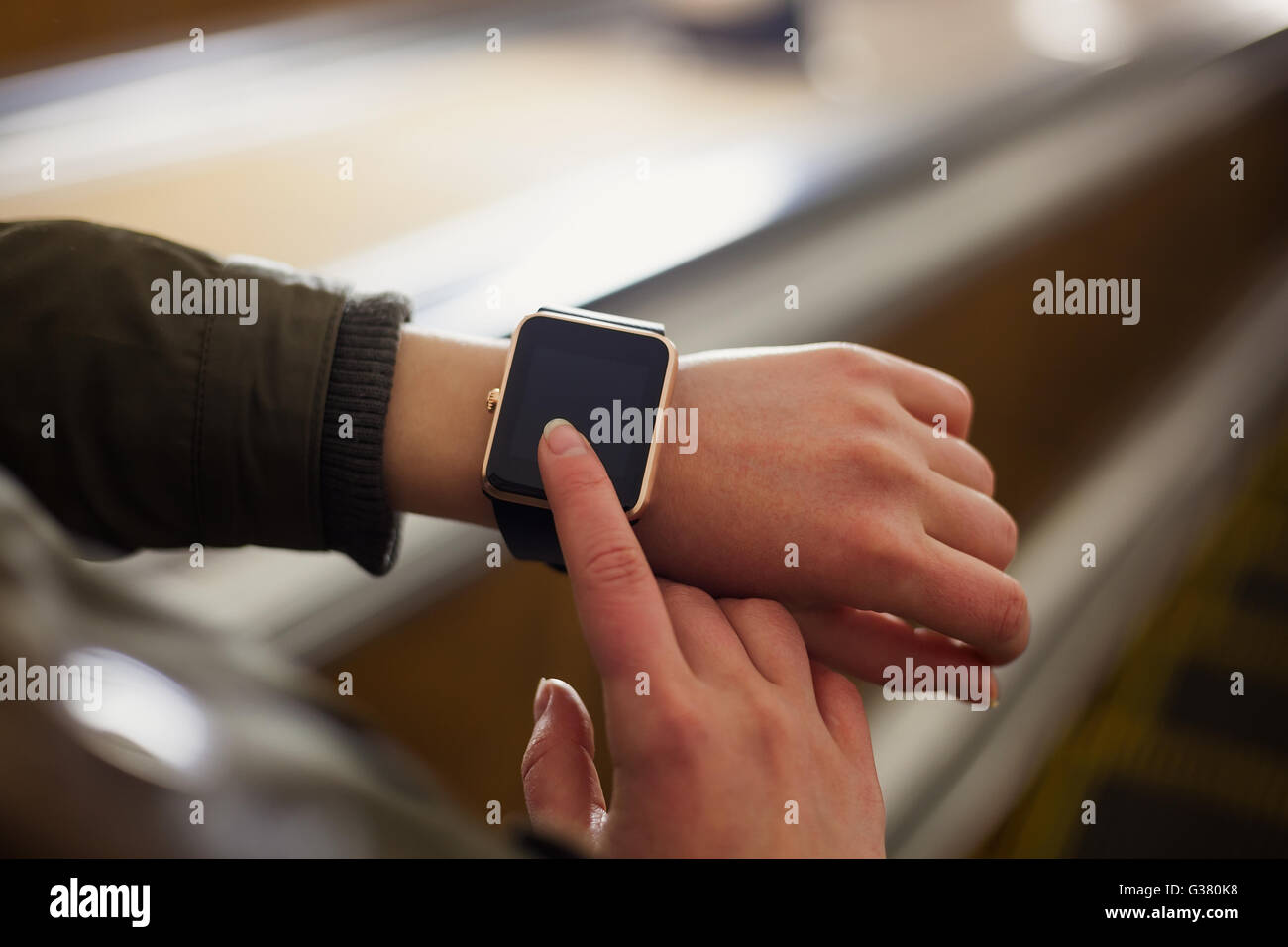 Female using smart watch on her hand while riding escalator stairs in ...