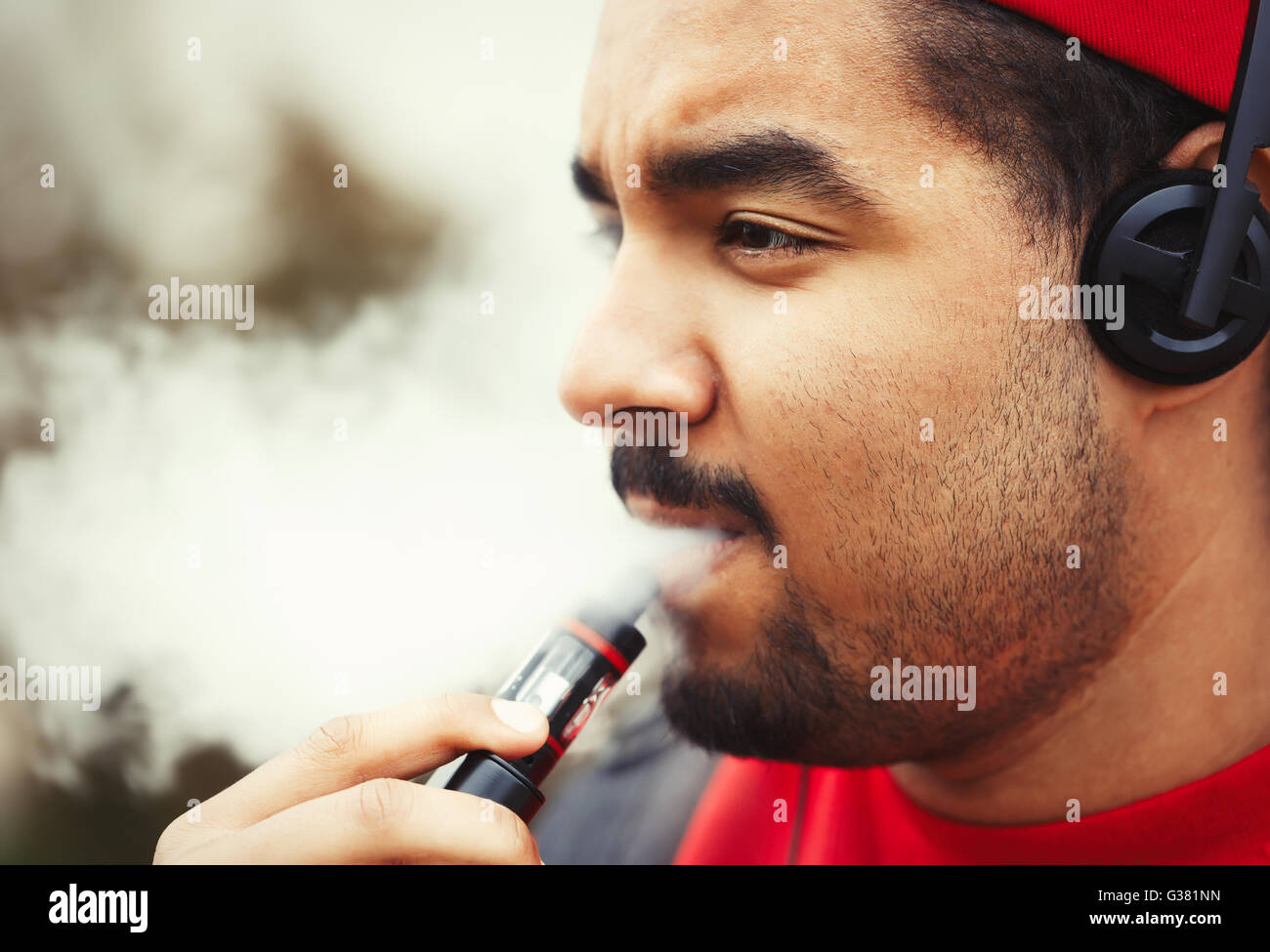 Portrait of black boy using modern e-cig vaporizer device for smoking ...