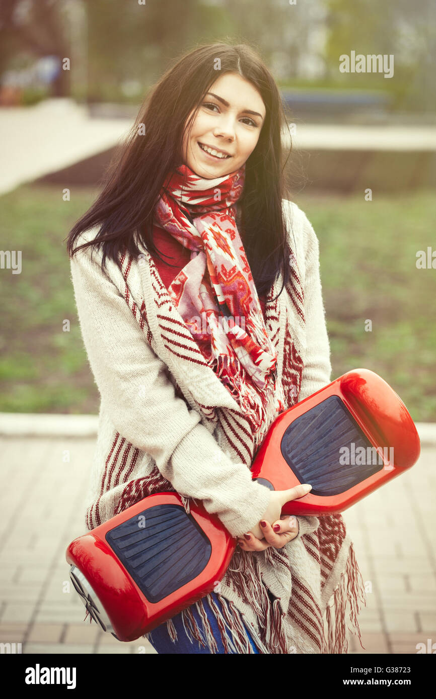 Brunette white girll holding modern red electric mini hover board ...