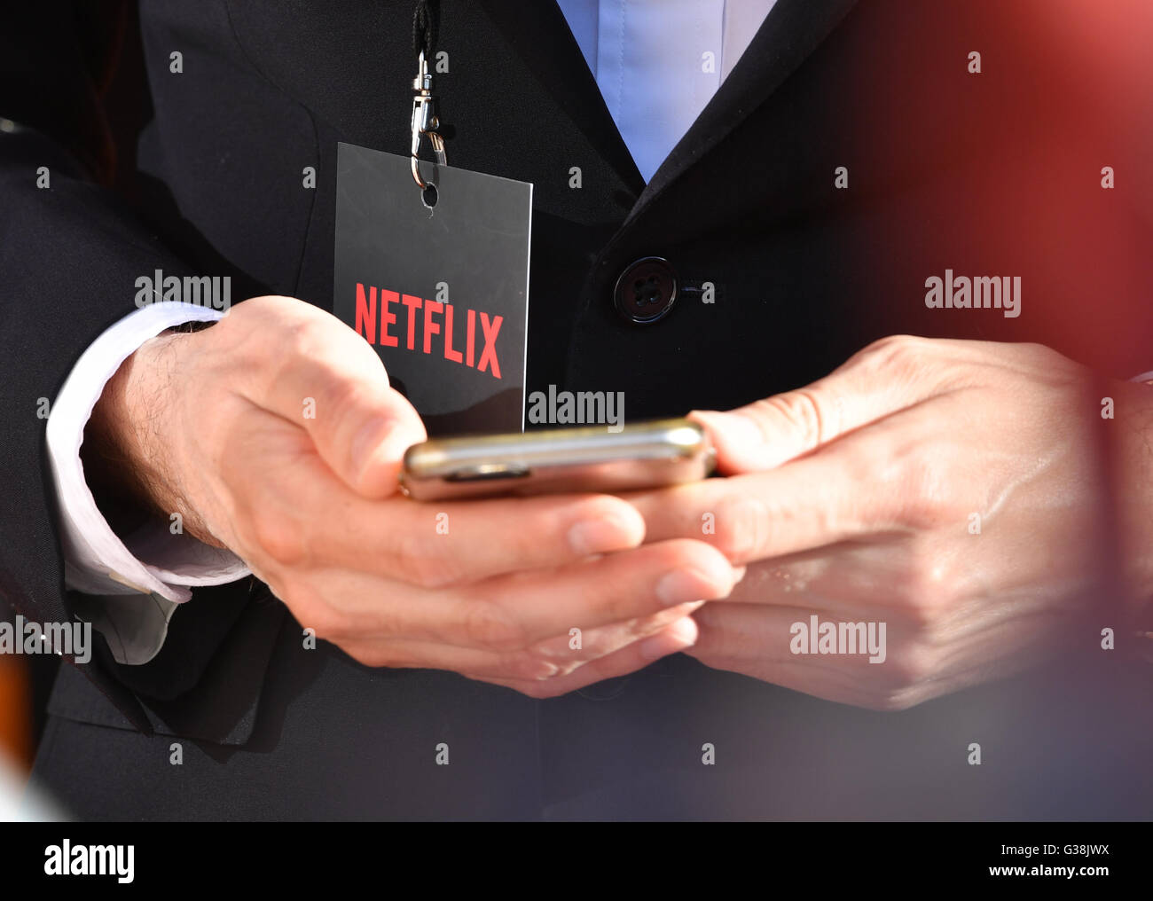 An employee stands on the red carpet with a Netflix badge and a ...