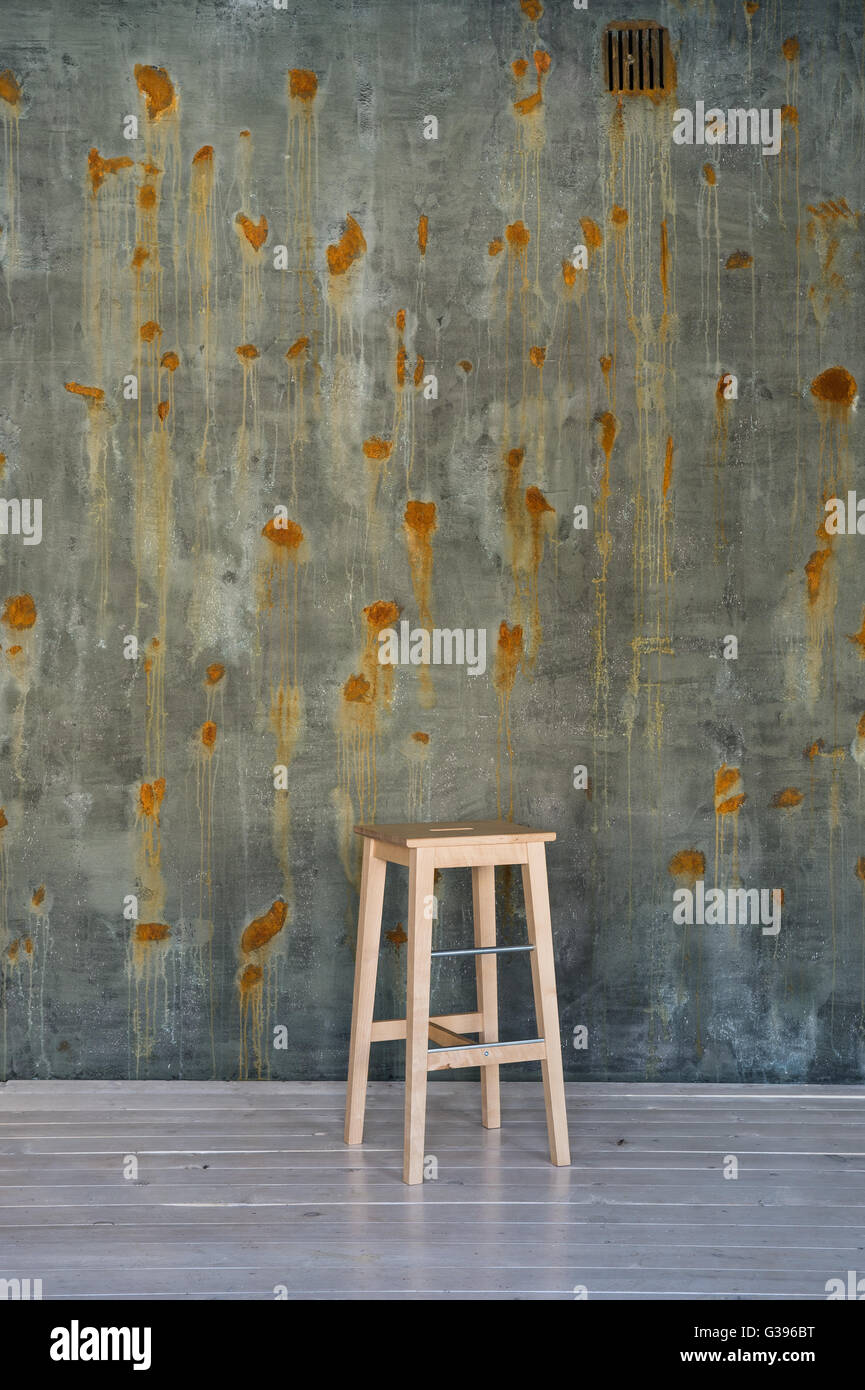 Bar stool chair on concrete wall with rust spots Stock Photo - Alamy