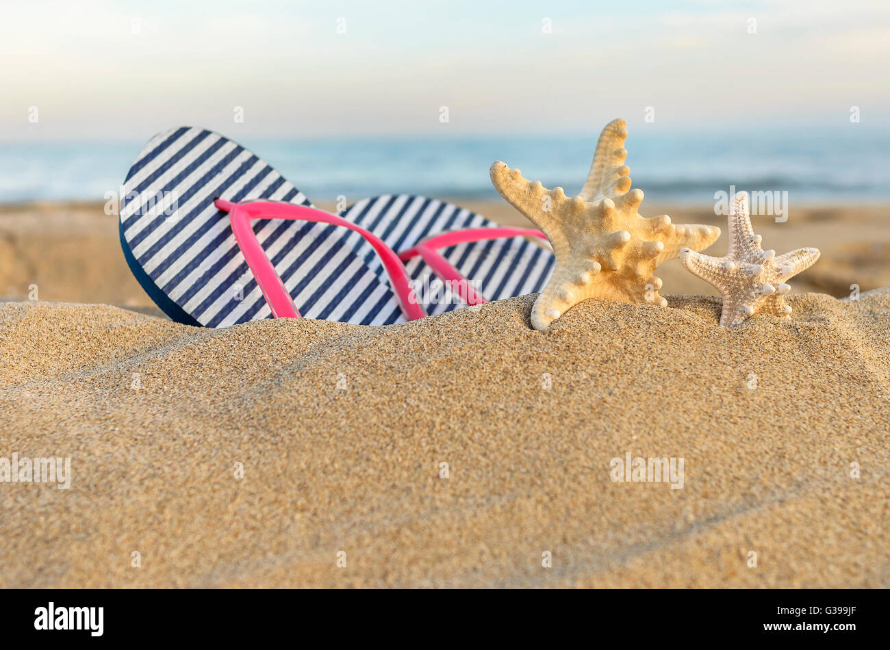Marine still life. Flip flops and starfish in the sand Stock Photo - Alamy