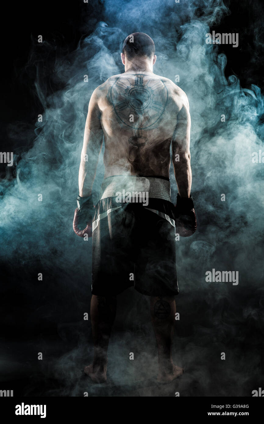 Muscular kickbox or muay thai fighter with tattoo standing back in ...