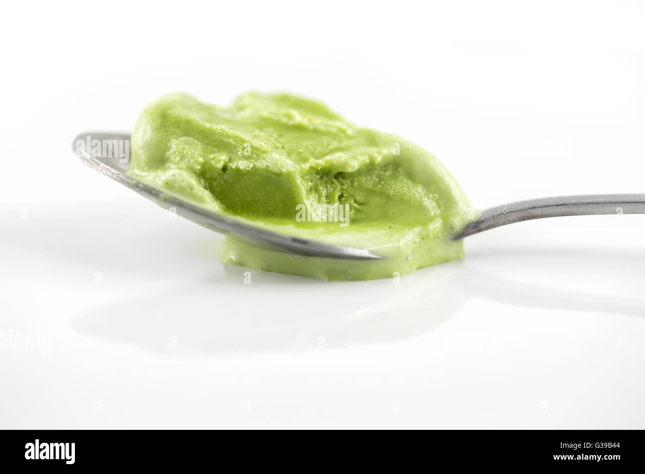 Close focus on green tea ice cream melting on teaspoon which putting on ...