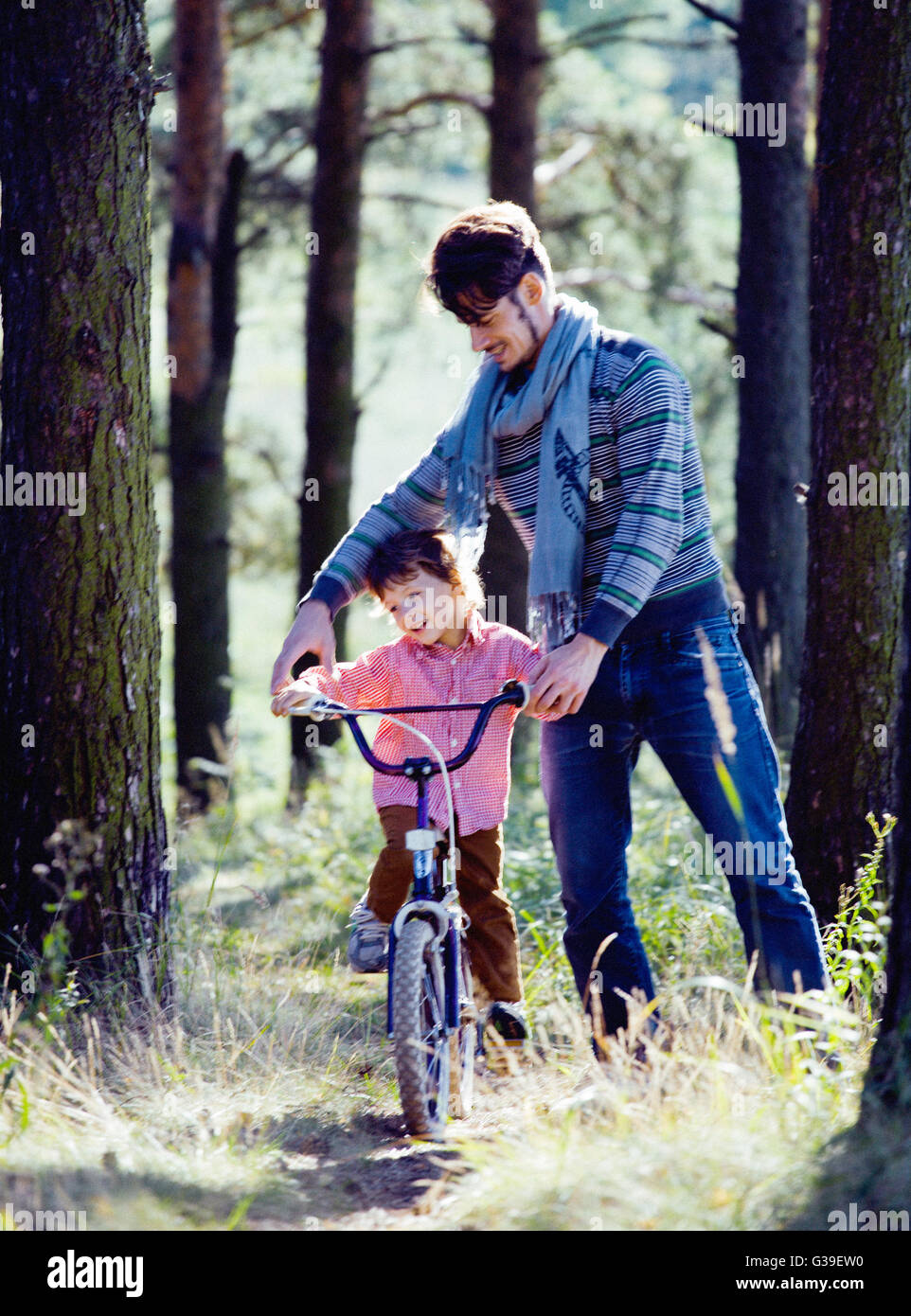 father learning his son to ride on bicycle outside in park Stock Photo ...