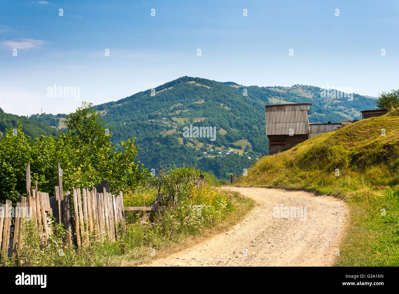 wooden stick fence in village in mountains with blue sky, green grass ...