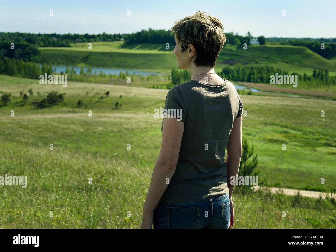 lonely woman standing with her back on green field Stock Photo - Alamy