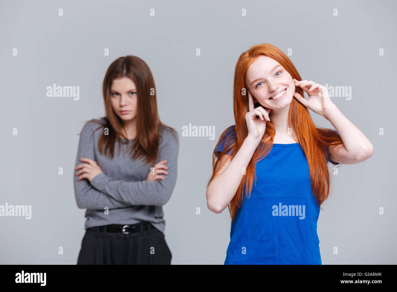 Portrait of two cheerful and unhappy young women over white background ...