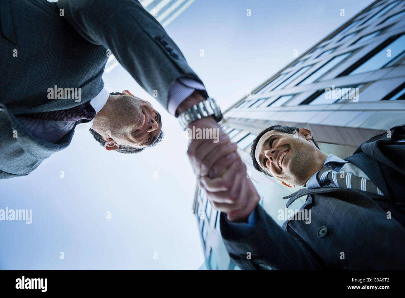 Corporate businessmen handshaking below building Stock Photo - Alamy
