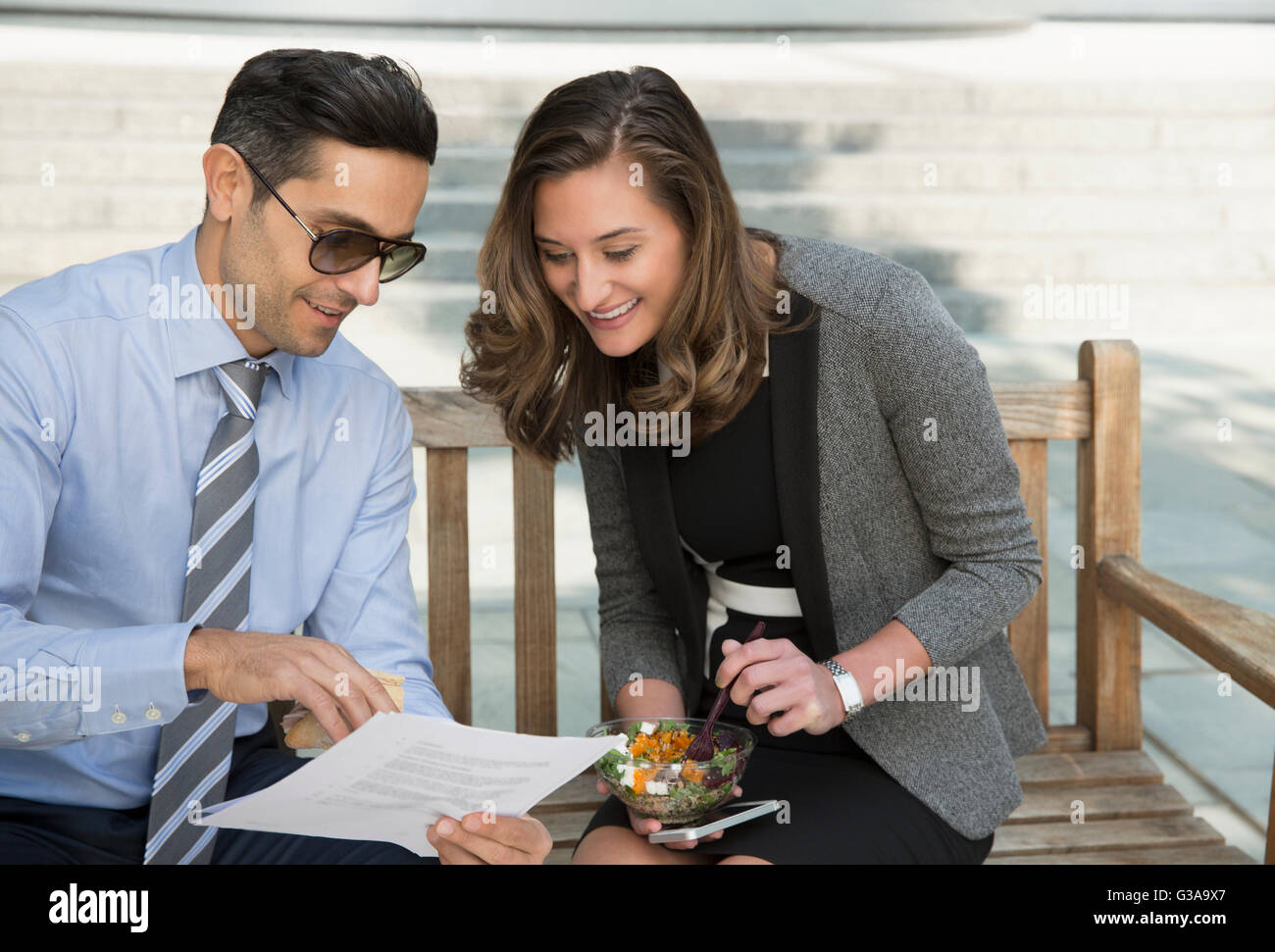 Corporate businessman and businesswoman eating lunch and reviewing ...