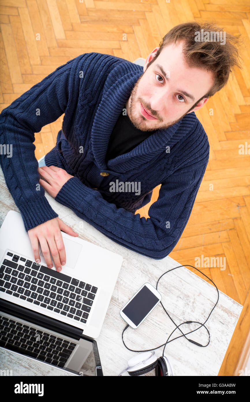 A young man working online from home with his laptop computer and ...