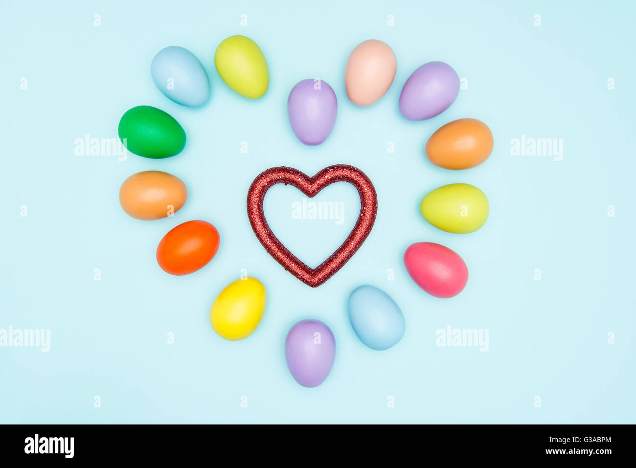Colorful easter eggs around the heart shape on pastel background Stock ...