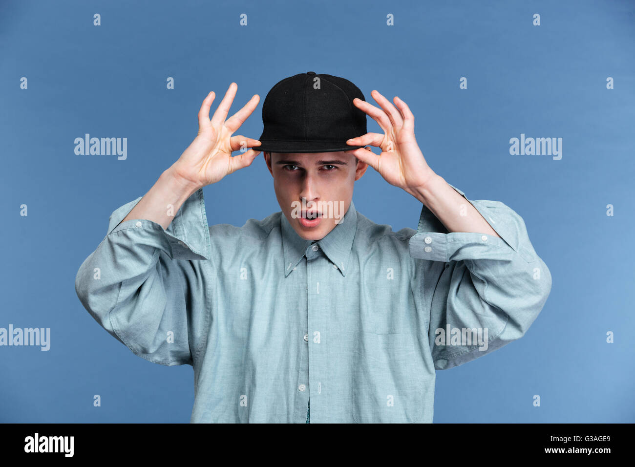 Young teenager putting cap on and posing isolated on the blue ...
