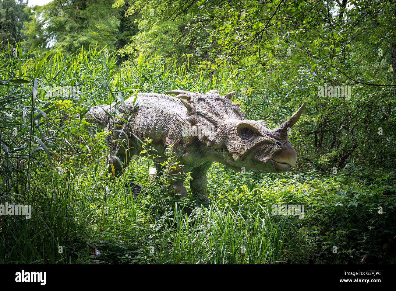 A dinosaur statue in a recreation park, greenery in background Stock ...