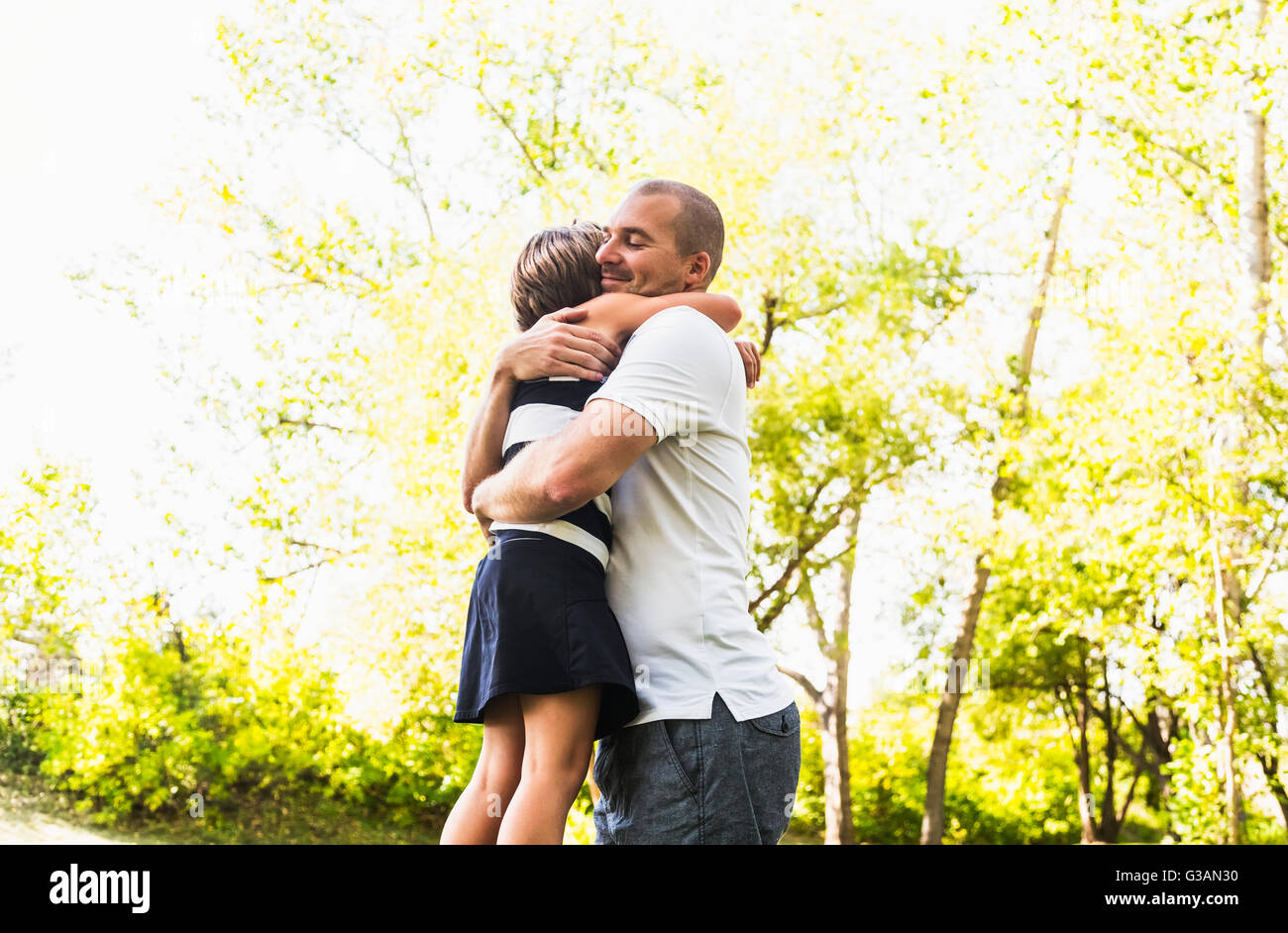 Father hugging his daughter in a park during a family outing; Edmonton ...