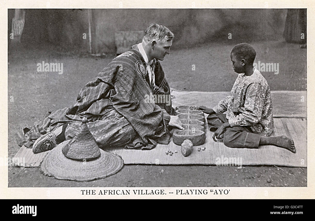 South Africa - European man and local boy play a game of Ayo Stock ...