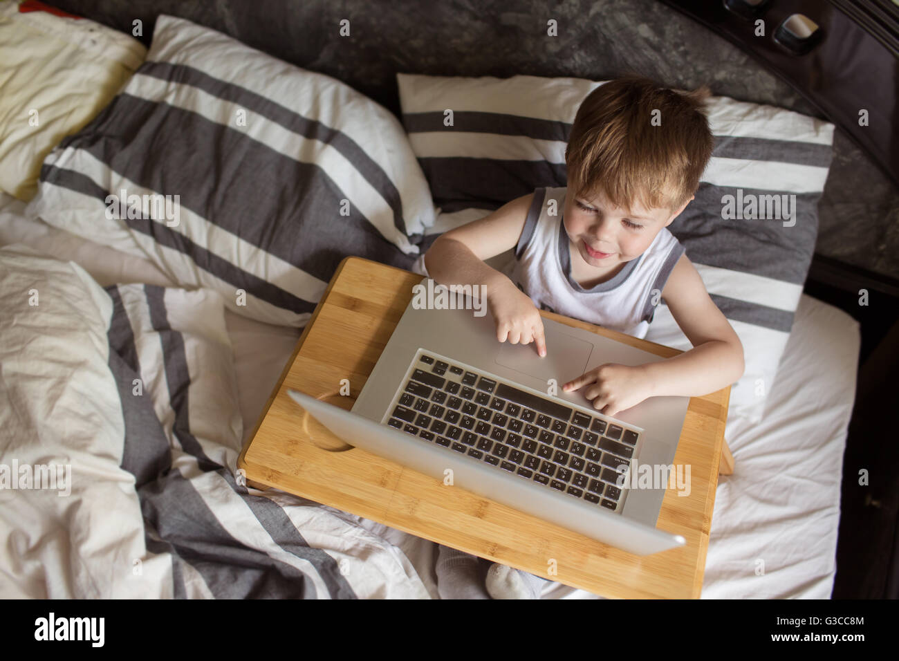 Toddler boy laying on the bed with laptop Stock Photo - Alamy