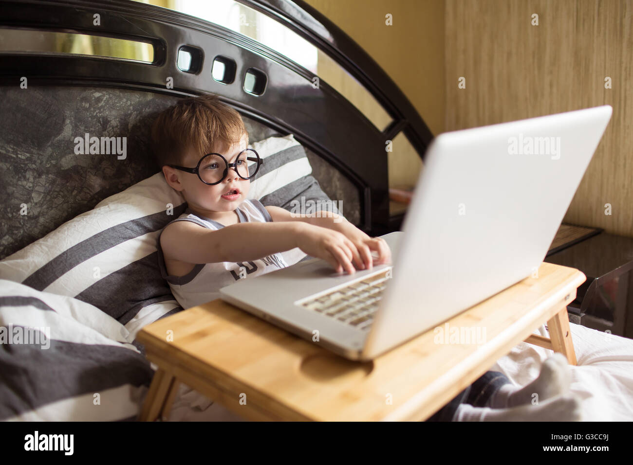 Toddler boy laying on the bed with laptop Stock Photo - Alamy