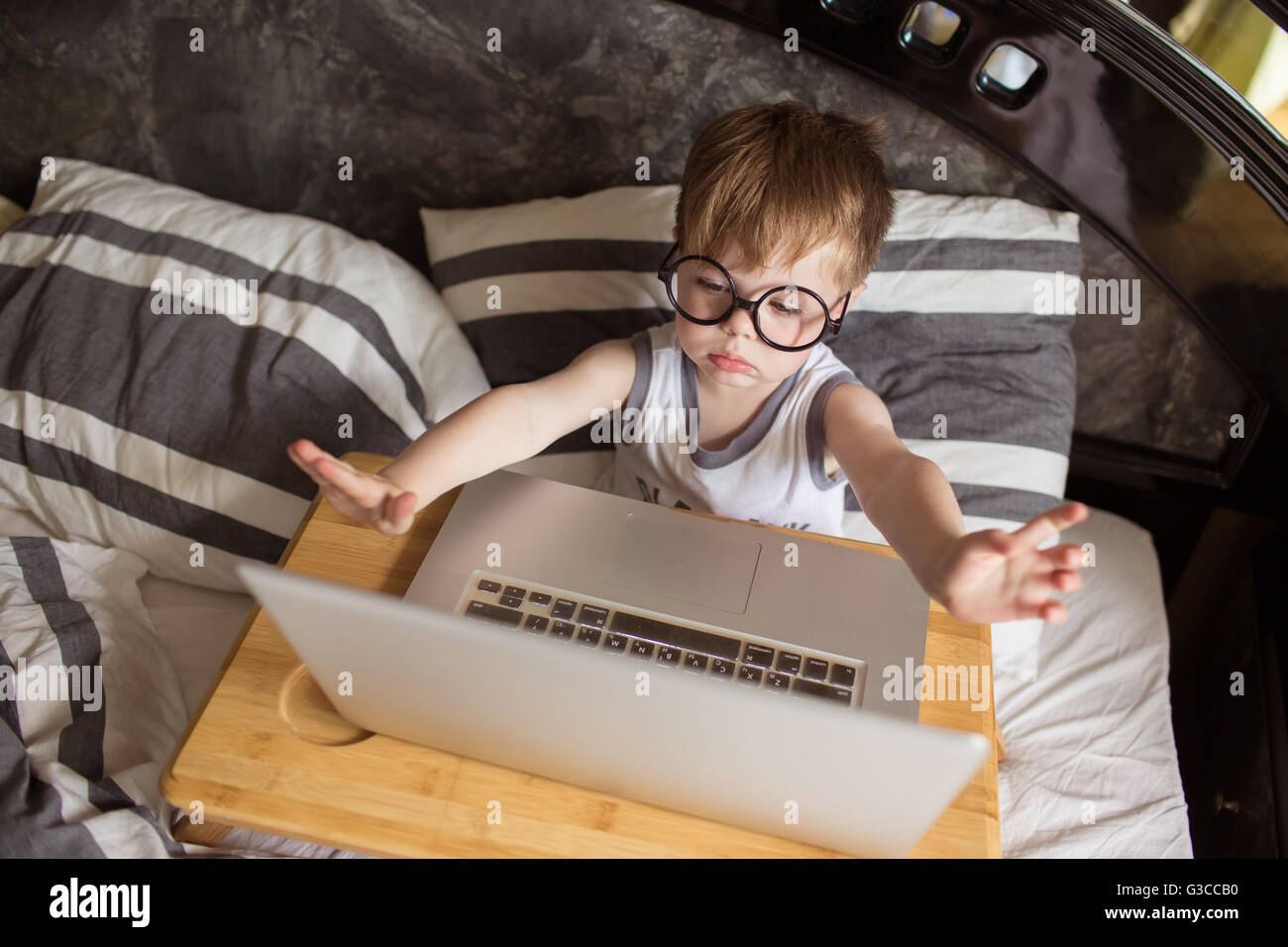 Toddler boy laying on the bed with laptop Stock Photo - Alamy