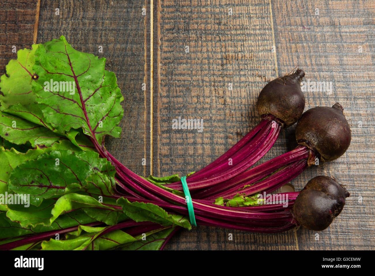 A bunch of fresh young beets with green beetroot on wooden background ...