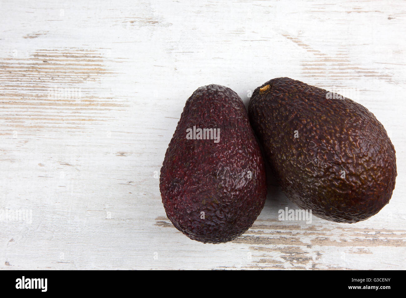 Two dark avocado fruit on white, old, wooden blacie.Horizontal, flat ...