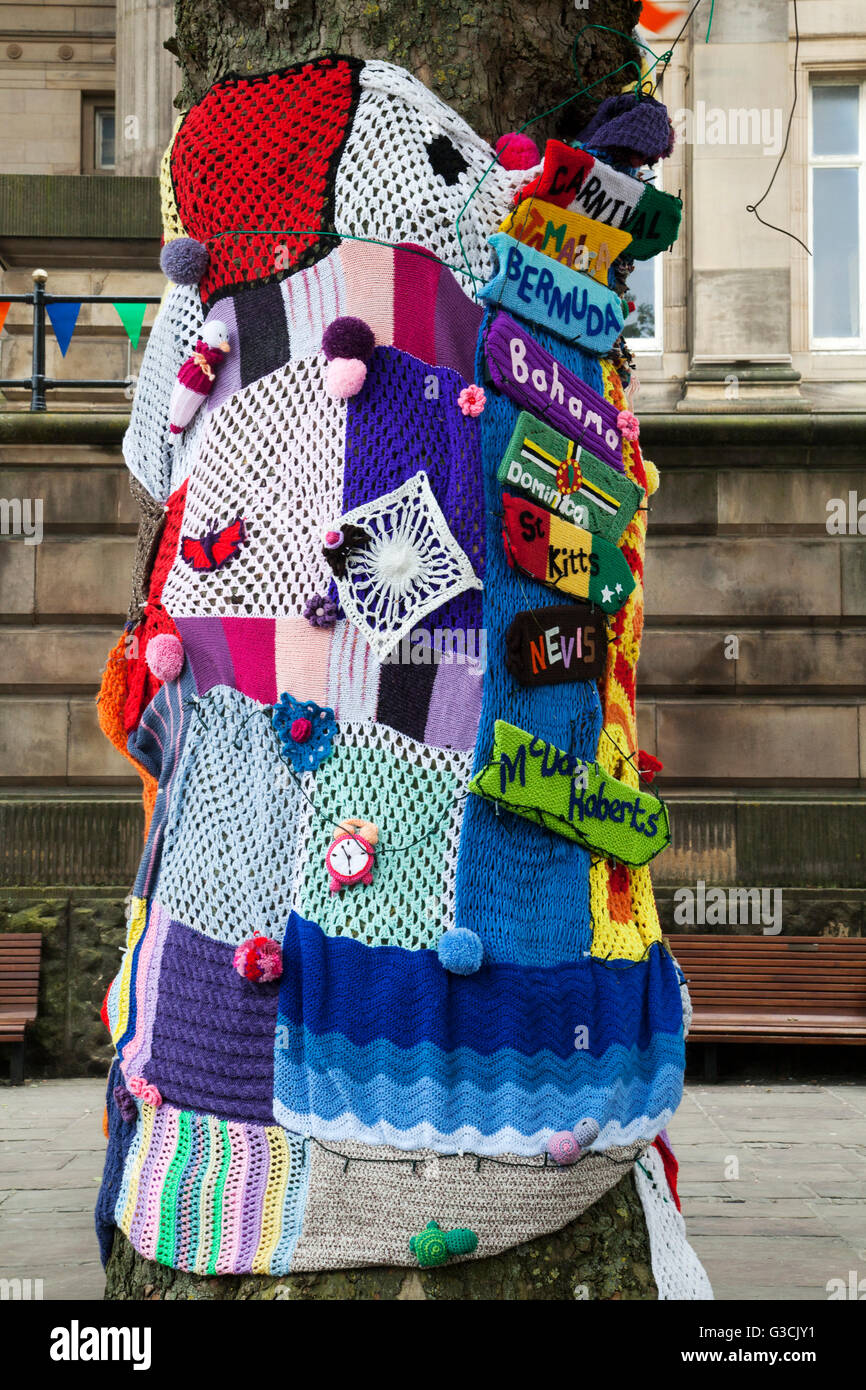 The trunk of a tree covered with a patchwork of coloured bright knitted ...