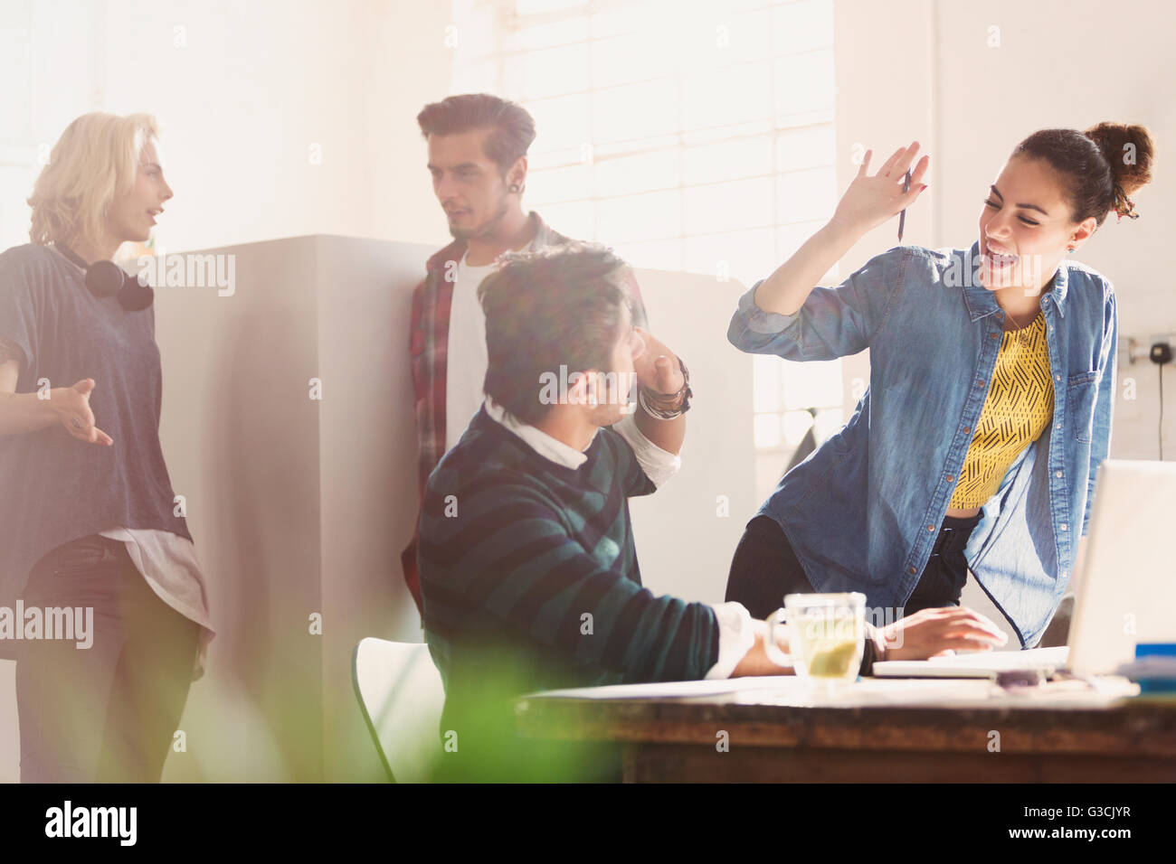 Creative young business people high fiving in office Stock Photo - Alamy