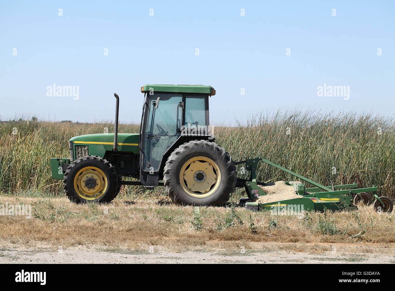 Empty tractor sitting in field with attached equipment Stock Photo - Alamy