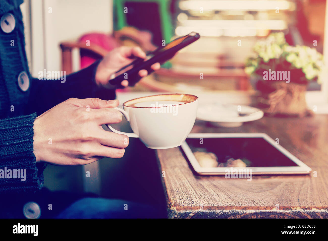 coffee on hand and playing smartphone in coffee shop with vintage tone ...