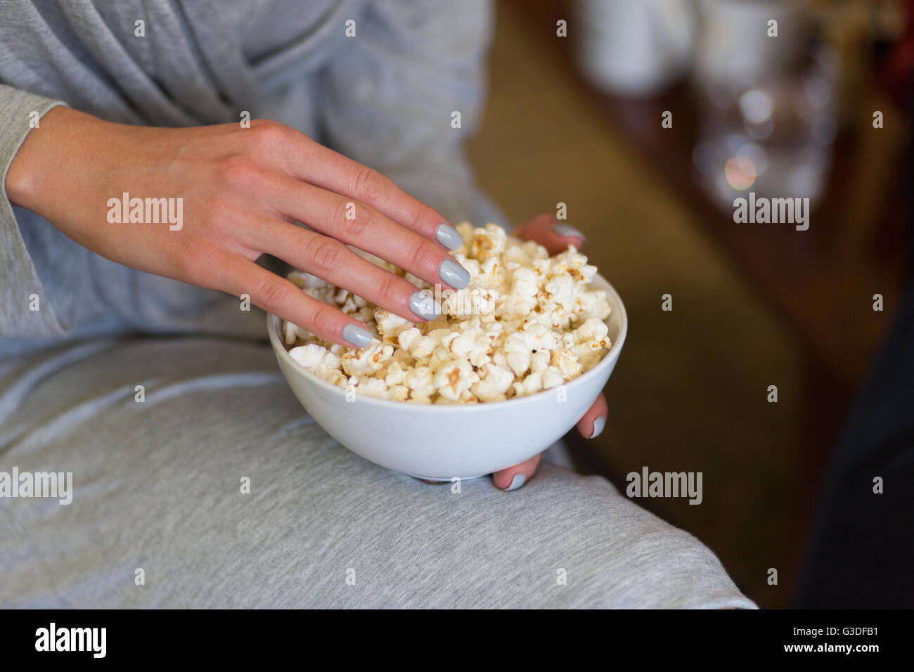 Lady's hand reaching for popcorn from a white bowl Stock Photo - Alamy