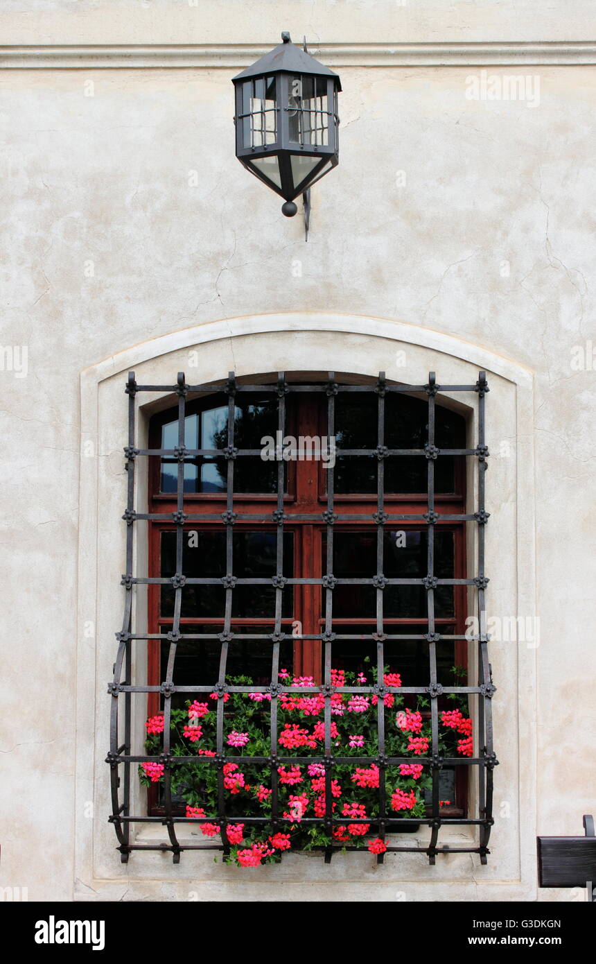 Medieval window with flowers, grate and a lamp Stock Photo - Alamy