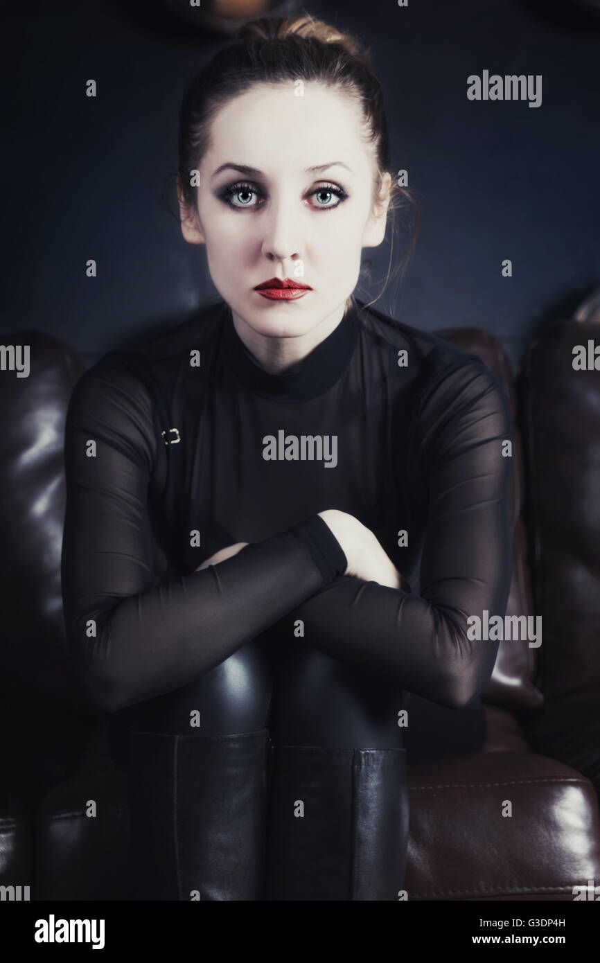 Portrait of a young woman sitting on leather sofa Stock Photo - Alamy