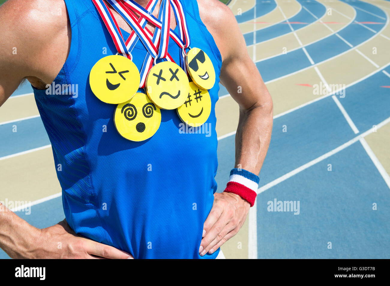 Athlete standing at running track wearing gold medals with bright ...