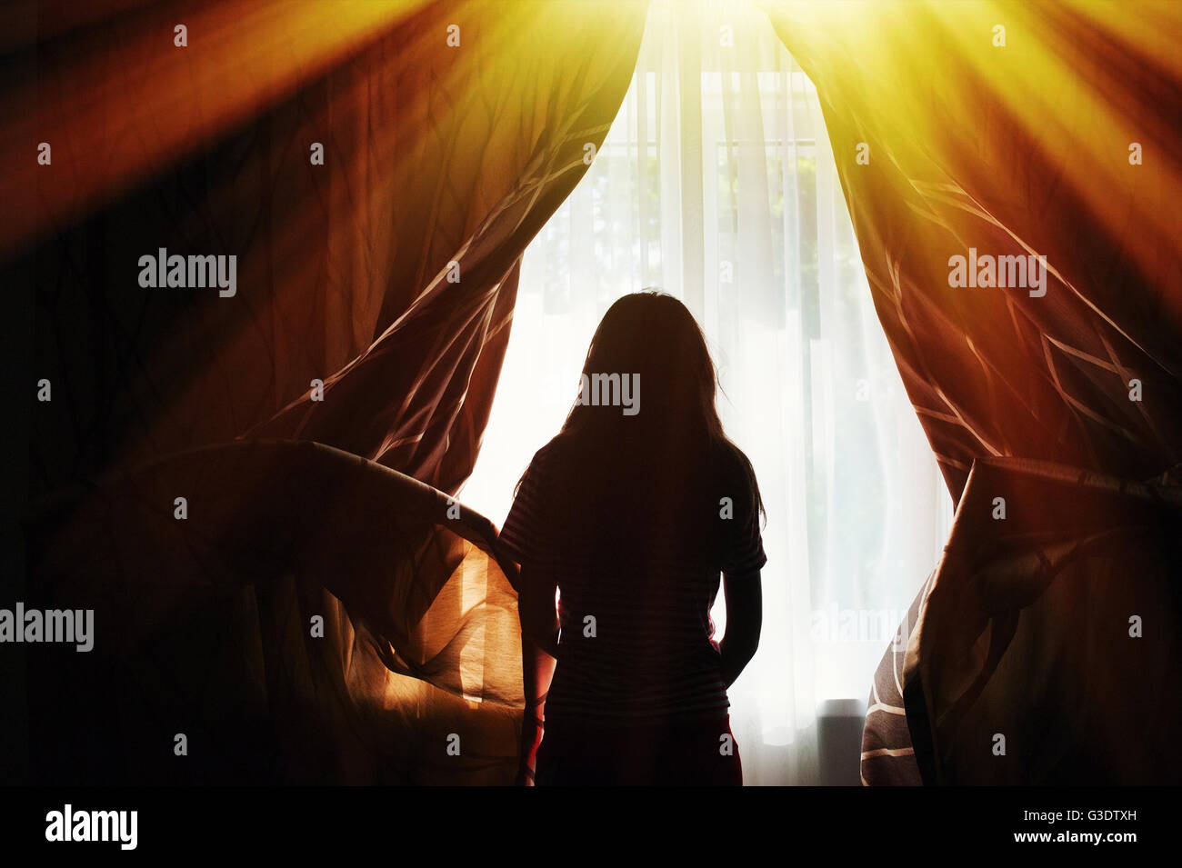 Silhouette of a young woman opens curtains at window Stock Photo - Alamy