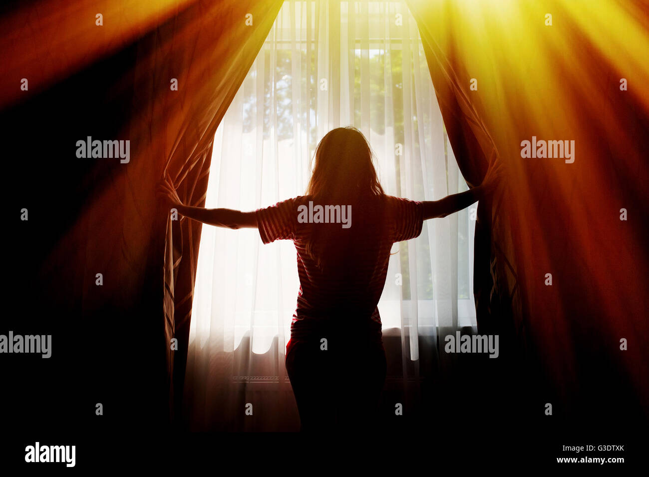 Silhouette of a young woman opens curtains at window Stock Photo - Alamy
