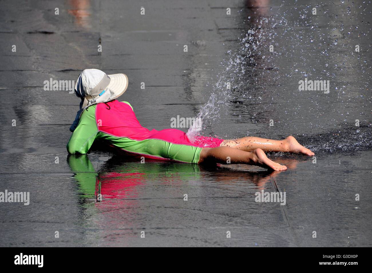 New York City: Little girl plays on a water jet on a hot summer ...