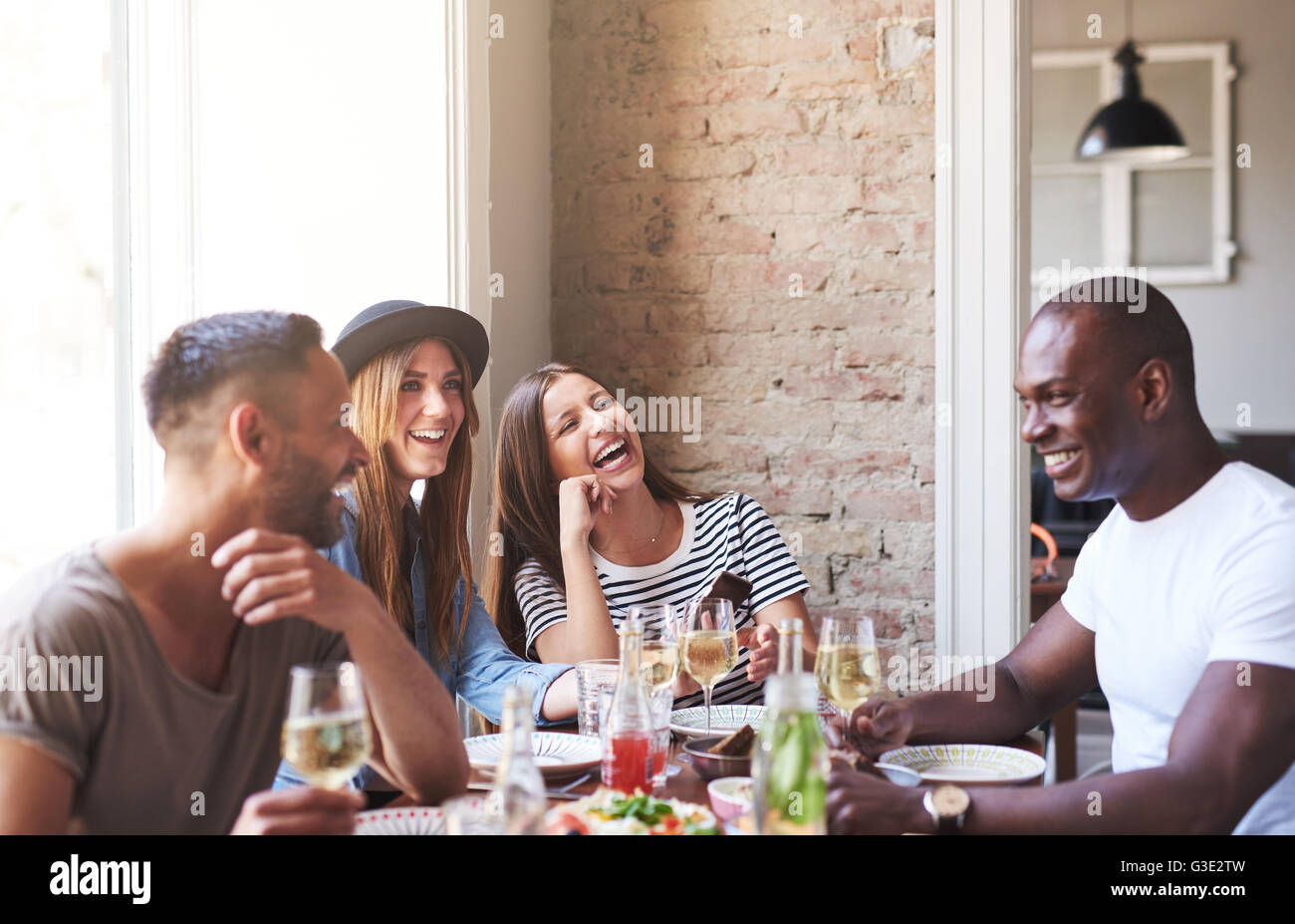 Diverse small group of four happy friends having wine and dinner ...
