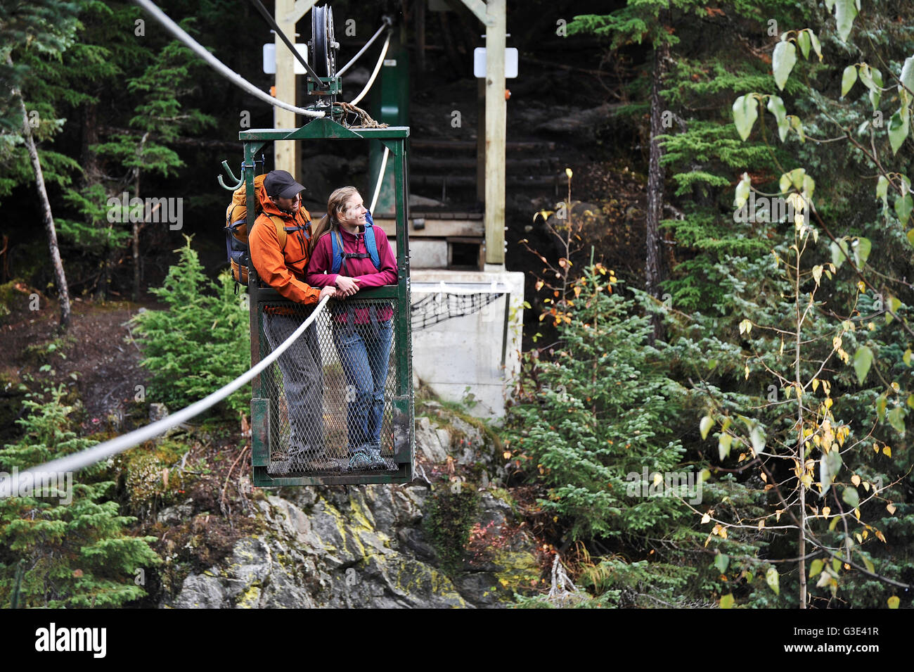 Backpacking couple use a hand tram to cross Winner Creek in the Chugach ...