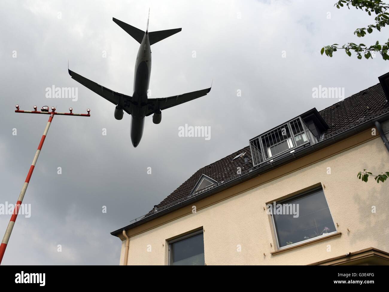 An airplane next to the roof of a residential building is about to land ...