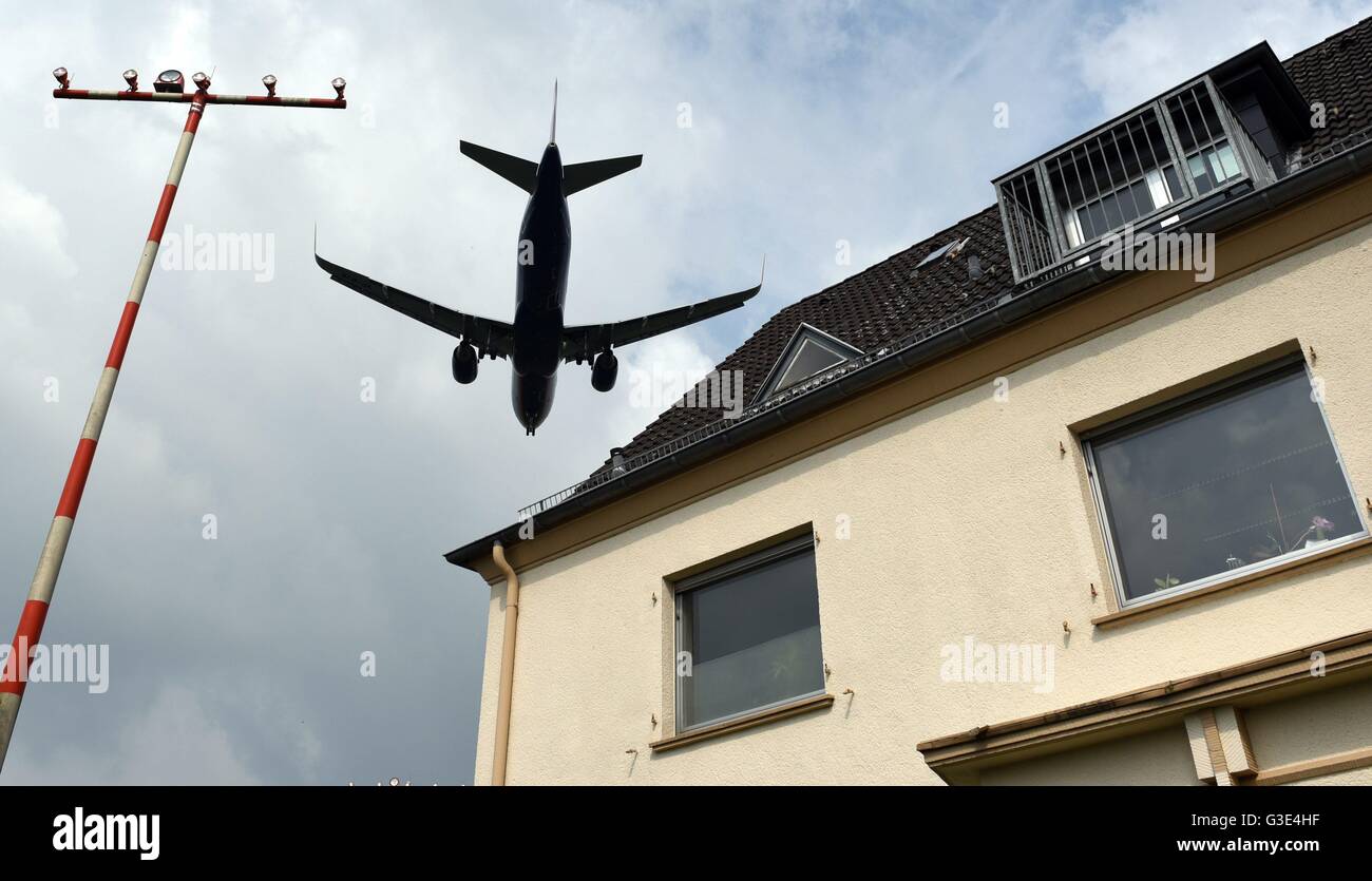 An airplane next to the roof of a residential building is about to land ...