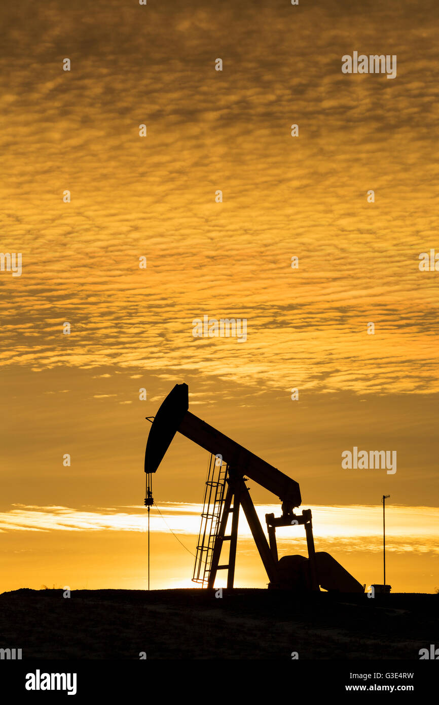 Silhouette of a pump jack at sunrise with the sun glowing on the ...