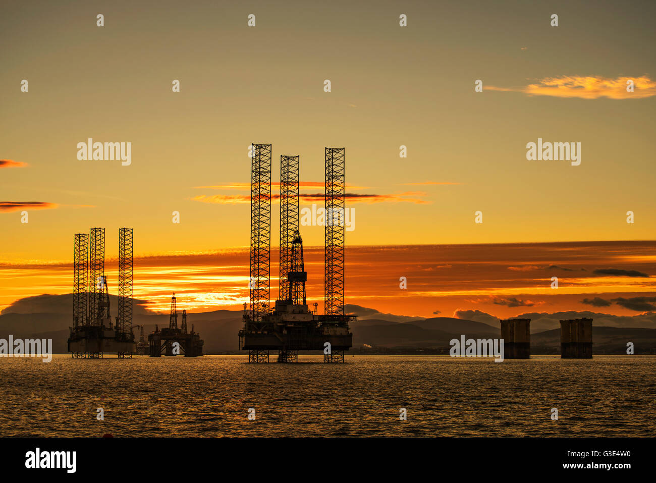 Oil drilling rigs out in the ocean with a view of the coastline and ...