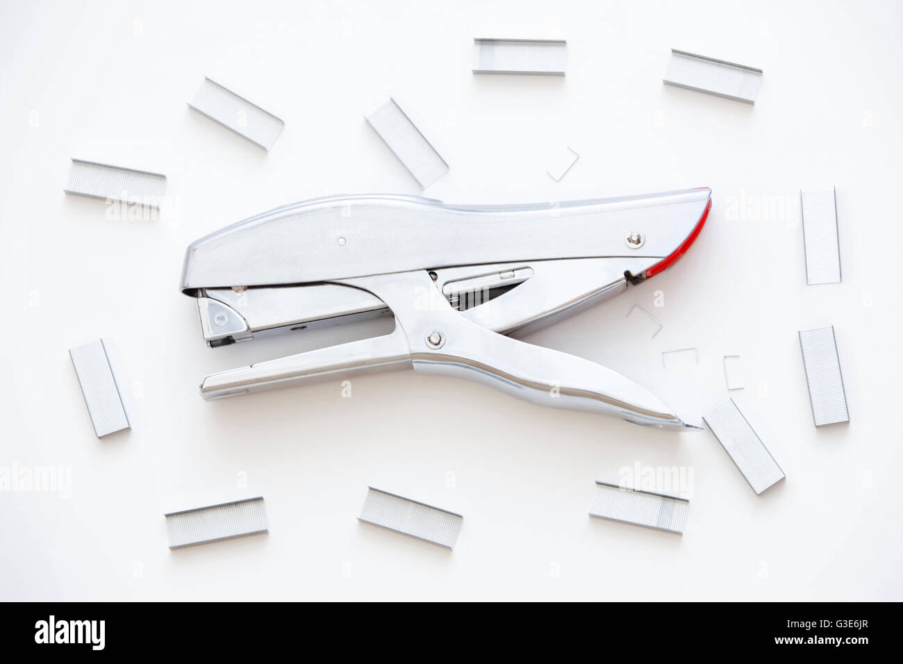 A top view of a group of staples scattered around the stapler on white ...